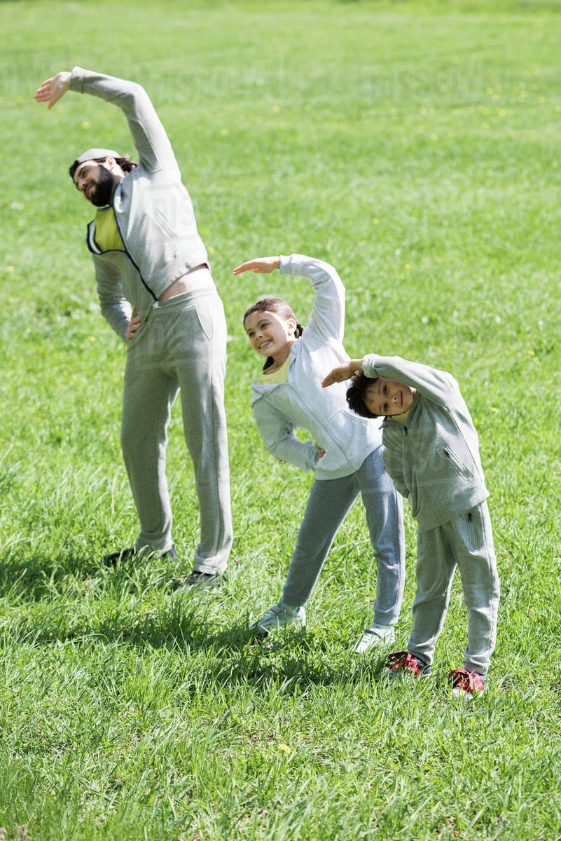 Happy sportive family doing physical exercise on grass - Royalty-free ...