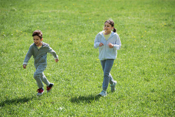 Sister and brother running on meadow in park - Royalty-free Stock Photo ...