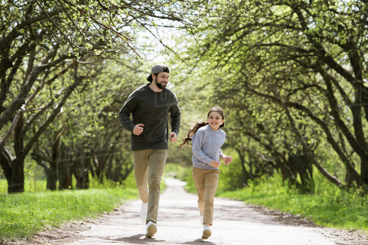 Happy father and daughter running on path in park - Royalty-free Stock ...