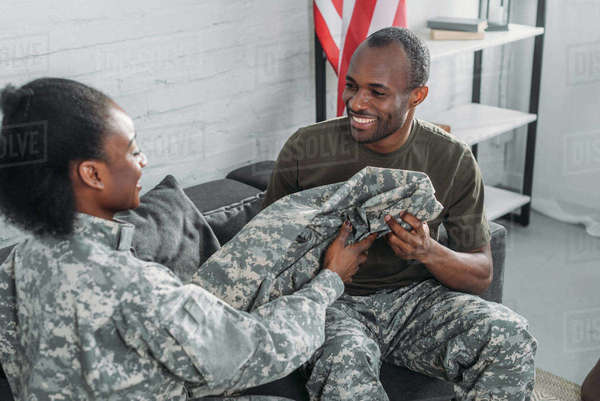 Couple of soldiers laughing together while sitting on sofa - Stock ...