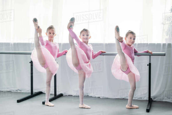 Beautiful little ballet dancers exercising and looking at camera in ...