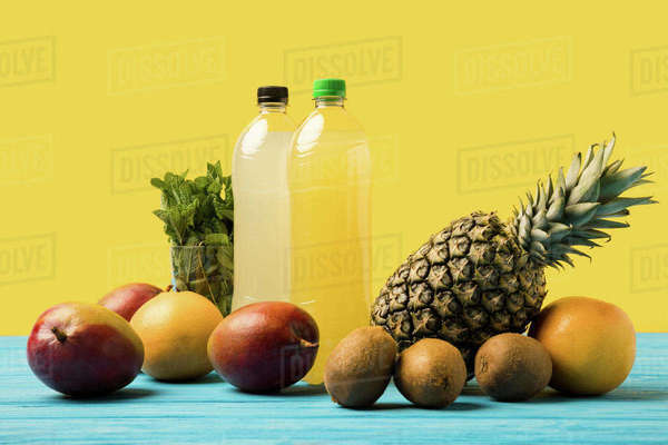 Fruity drinks in plastic bottles and fresh ripe tropical fruits on ...