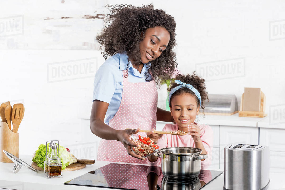 African american mom and daughter cooking on electric stove together ...
