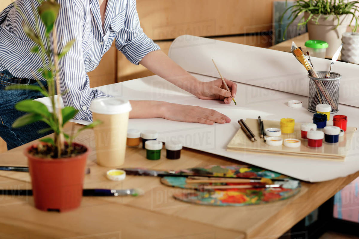 Cropped shot of young female artist drawing on table in studio ...
