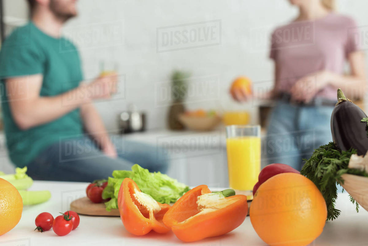 Cropped image of vegan couple talking in kitchen with fruits and ...