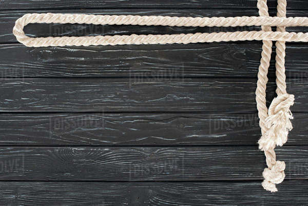 Top view of white nautical rope with knots on dark wooden tabletop ...