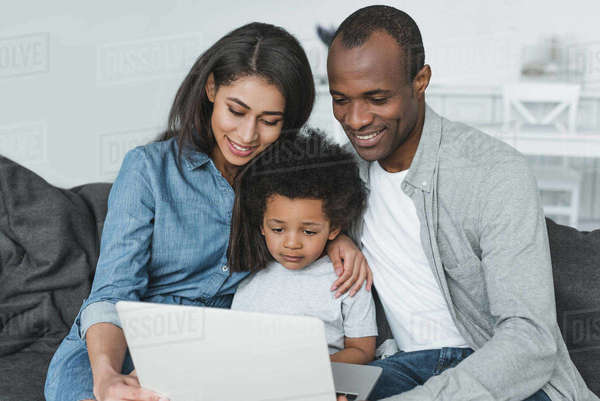 African american parents and son using laptop in living room - Royalty ...
