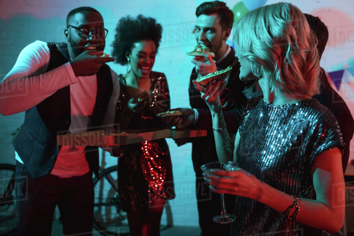 Partying diverse people eating pizza and holding drinks - Royalty-free ...