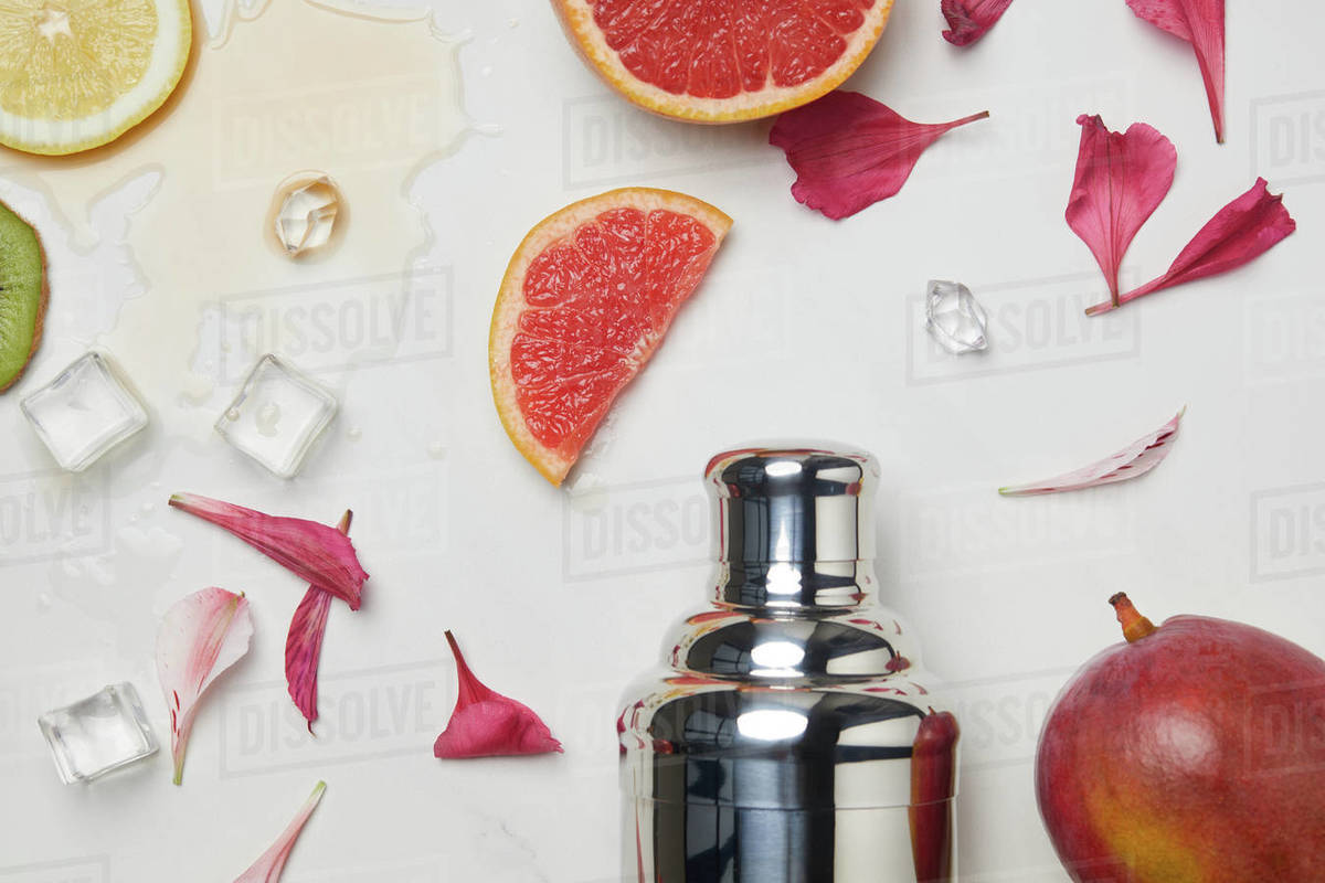 Flat lay with cocktail shaker, ice cubes, flower petals and arranged ...