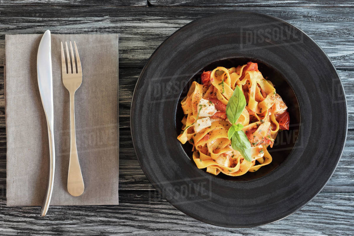 Top view of delicious italian pasta and fork with knife on wooden table ...