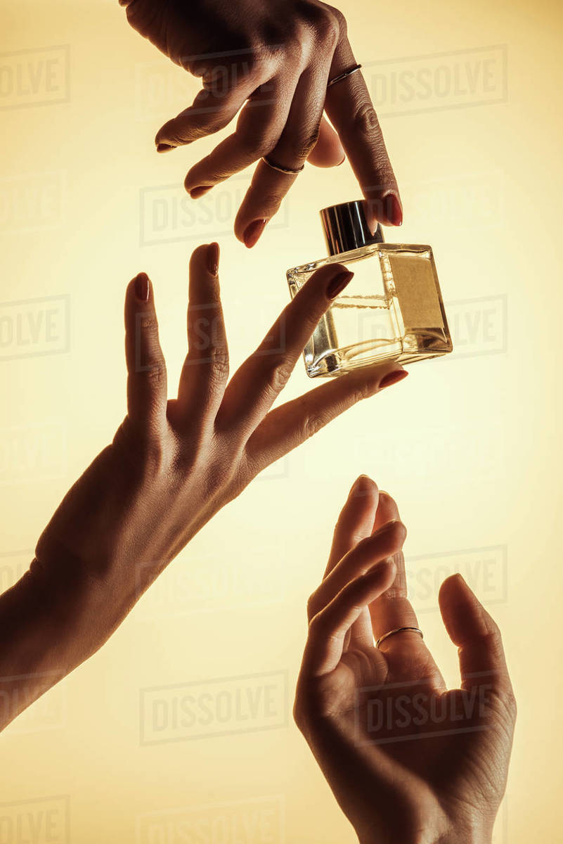 Cropped view of female hands with perfume, isolated on yellow - Stock ...