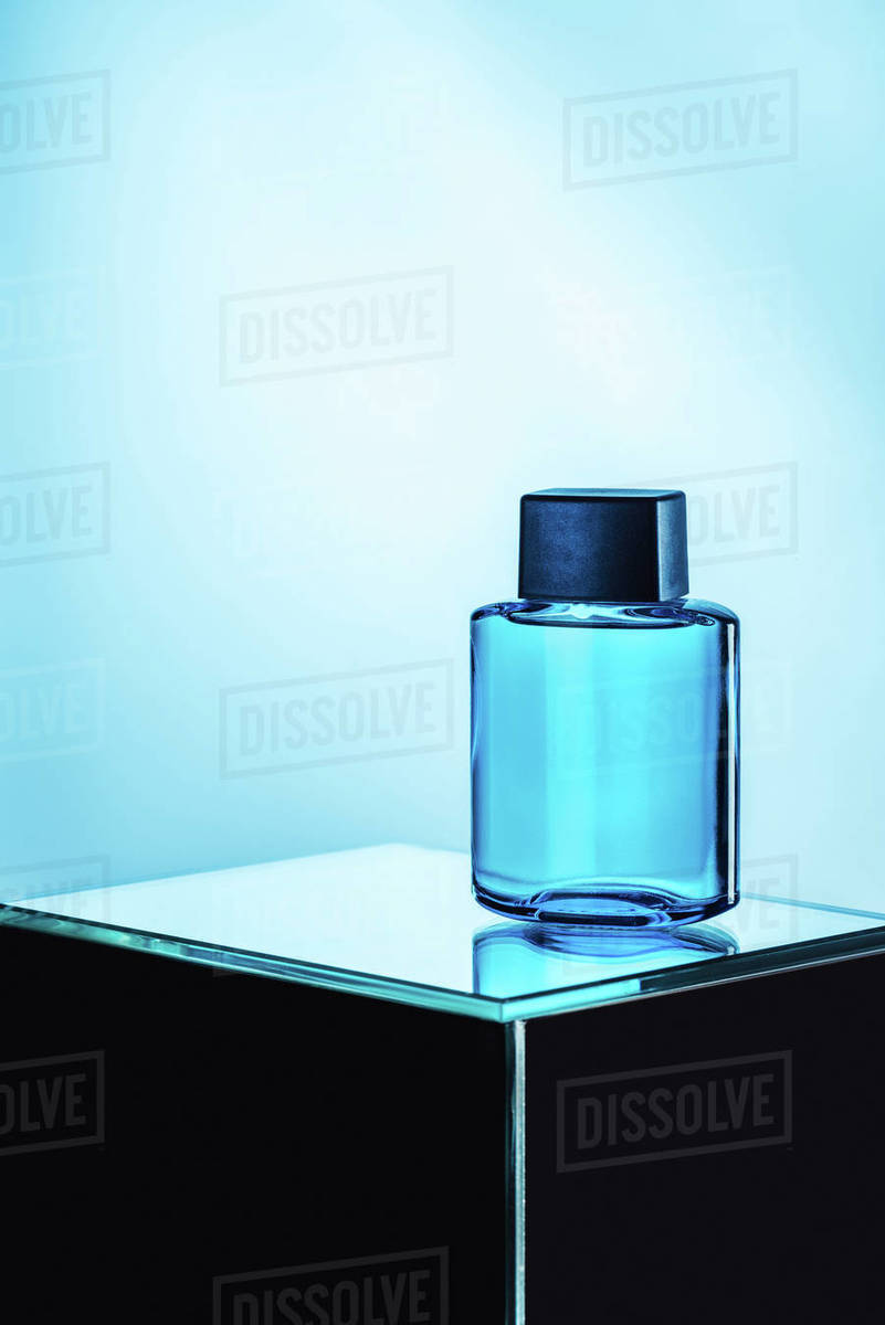 Mens perfume in blue spray bottle, on blue - Stock Photo - Dissolve