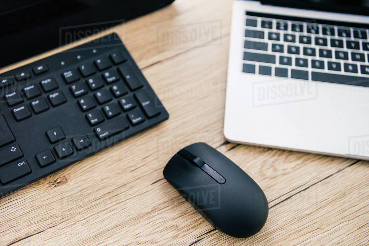 Elevated view of computer keyboard, computer mouse and laptop at table ...