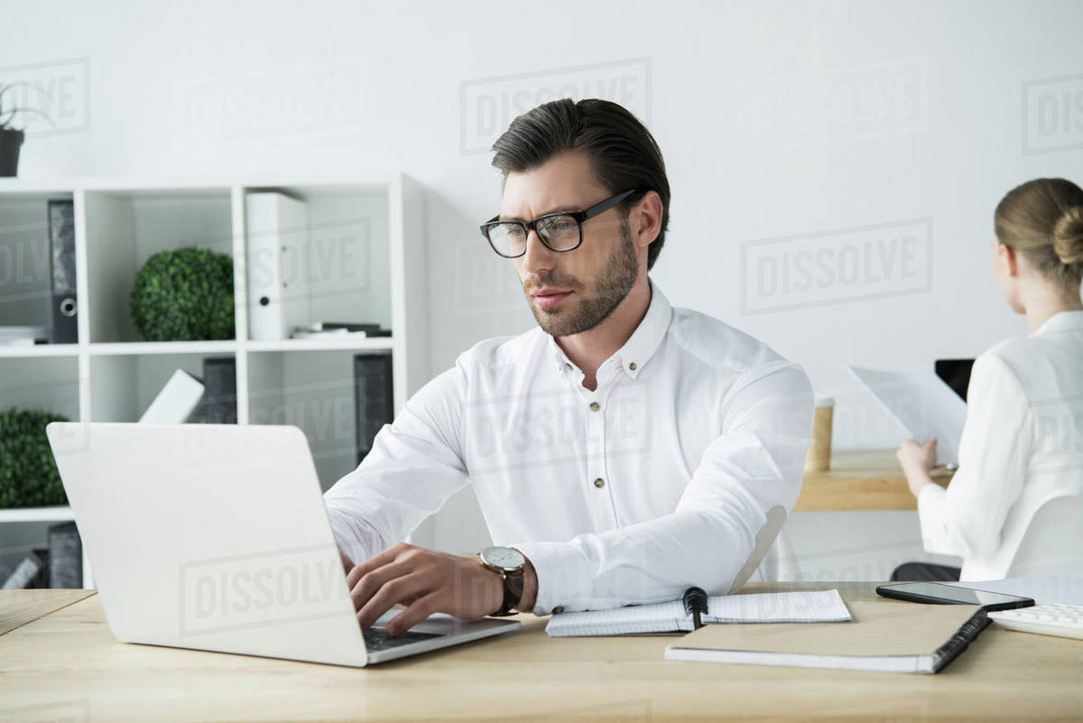 Focused young businessman working with laptop at modern office with ...
