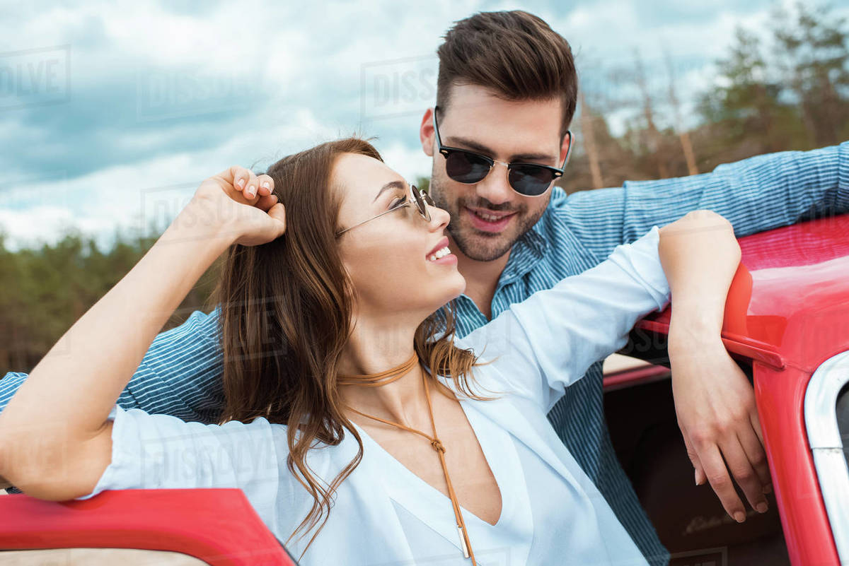 Smiling beautiful couple hugging near car - Stock Photo - Dissolve