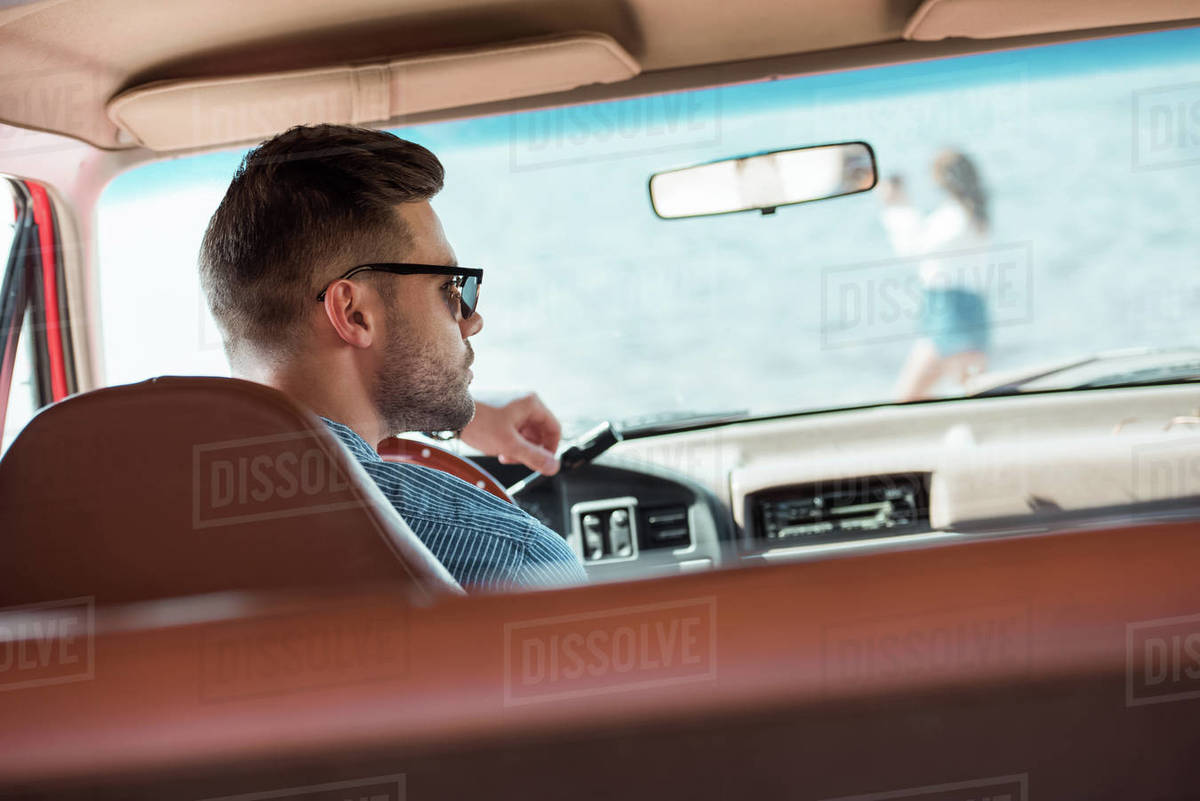 Back view of male driver in sunglasses sitting in car during road trip ...