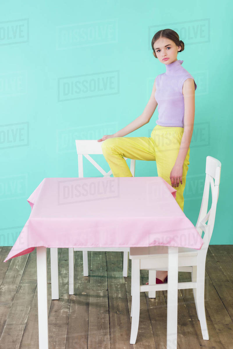 fashionable teen girl posing at table and chairs in dining room ...