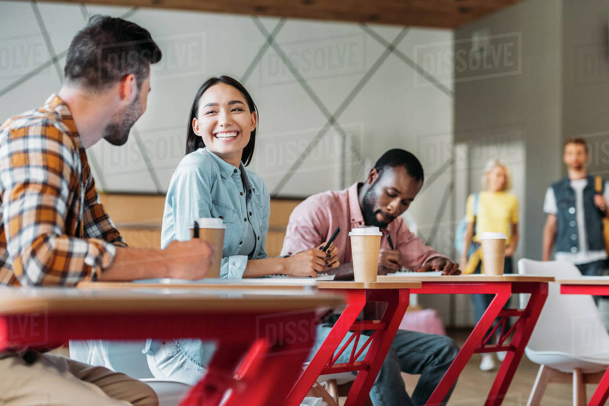 Happy young students chatting at classroom of college - Royalty-free ...