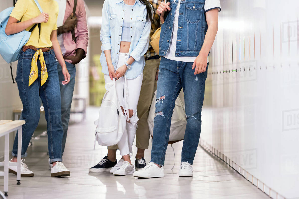 Cropped shot of young stylish students standing together in college ...
