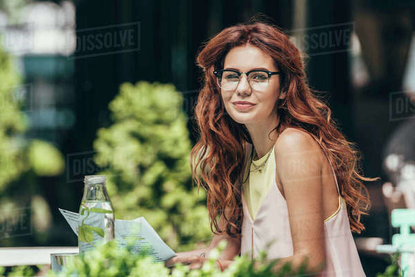 Side view of attractive young woman in eyeglasses with newspaper in ...