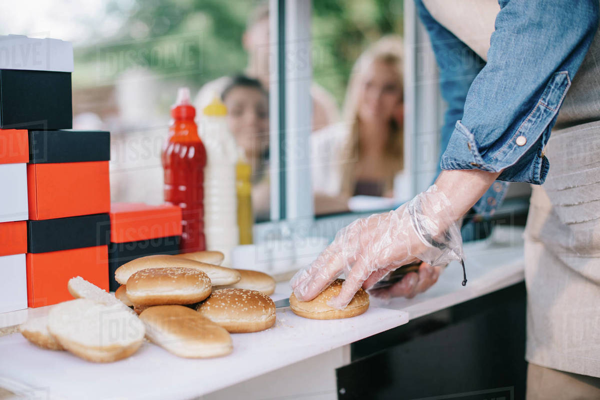 Cropped shot of male chef cutting buns white cooking at food truck ...