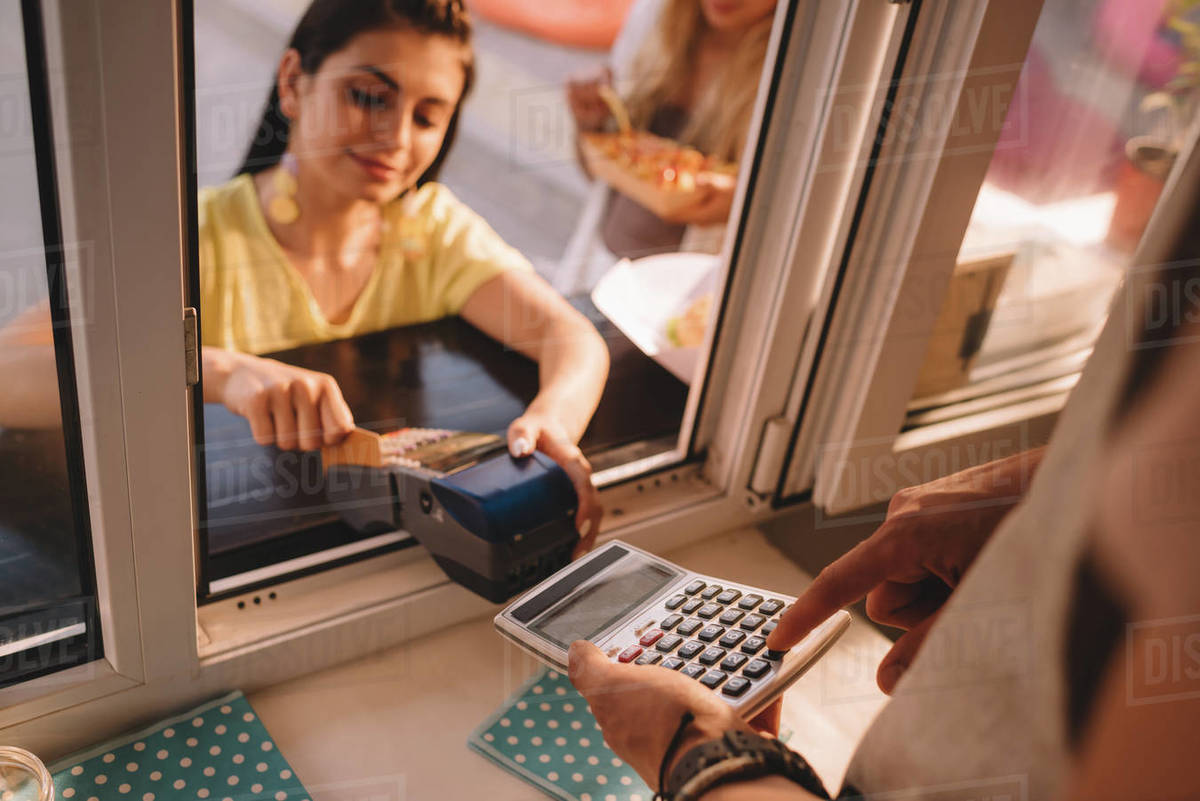 Cropped image of customer paying with credit card at food truck ...