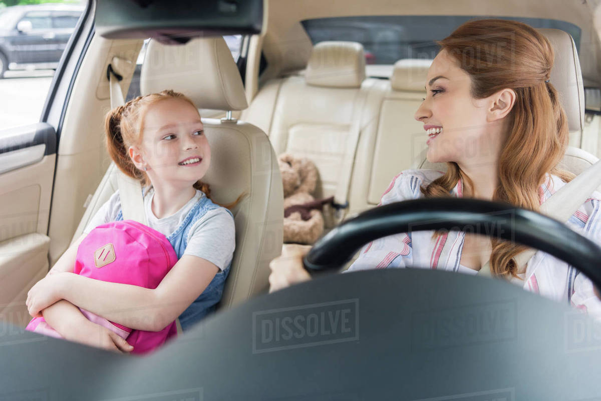 Portrait of smiling mother driving car with daughter on passengers seat ...