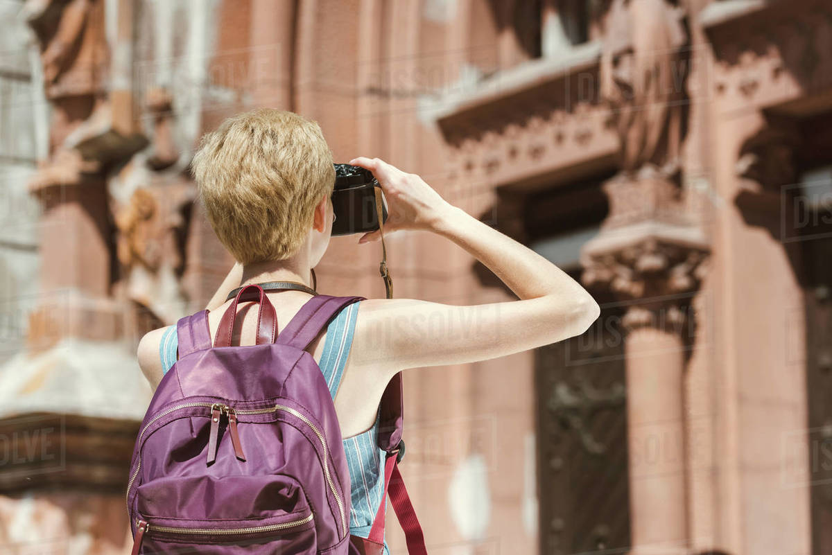 Back view of tourist with backpack taking photo in city - Royalty-free ...