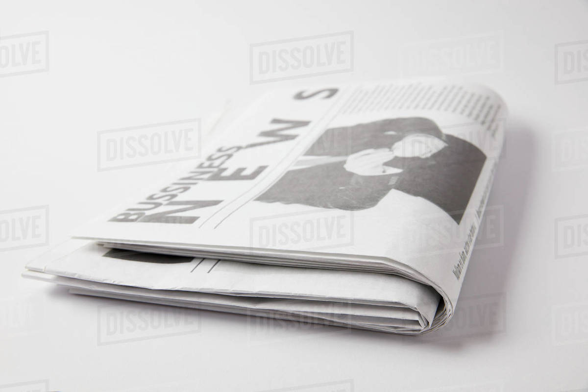 Close up of pile of business newspapers, on white - Stock Photo - Dissolve