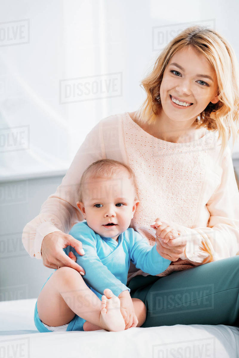Mother sitting with happy little child on bed at home - Stock Photo ...
