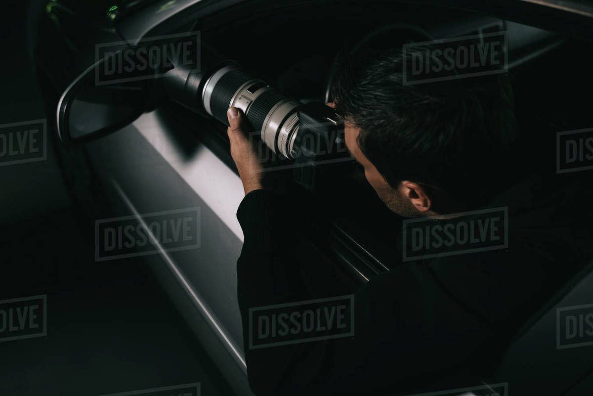 Back view of undercover agent doing surveillance by camera with object ...
