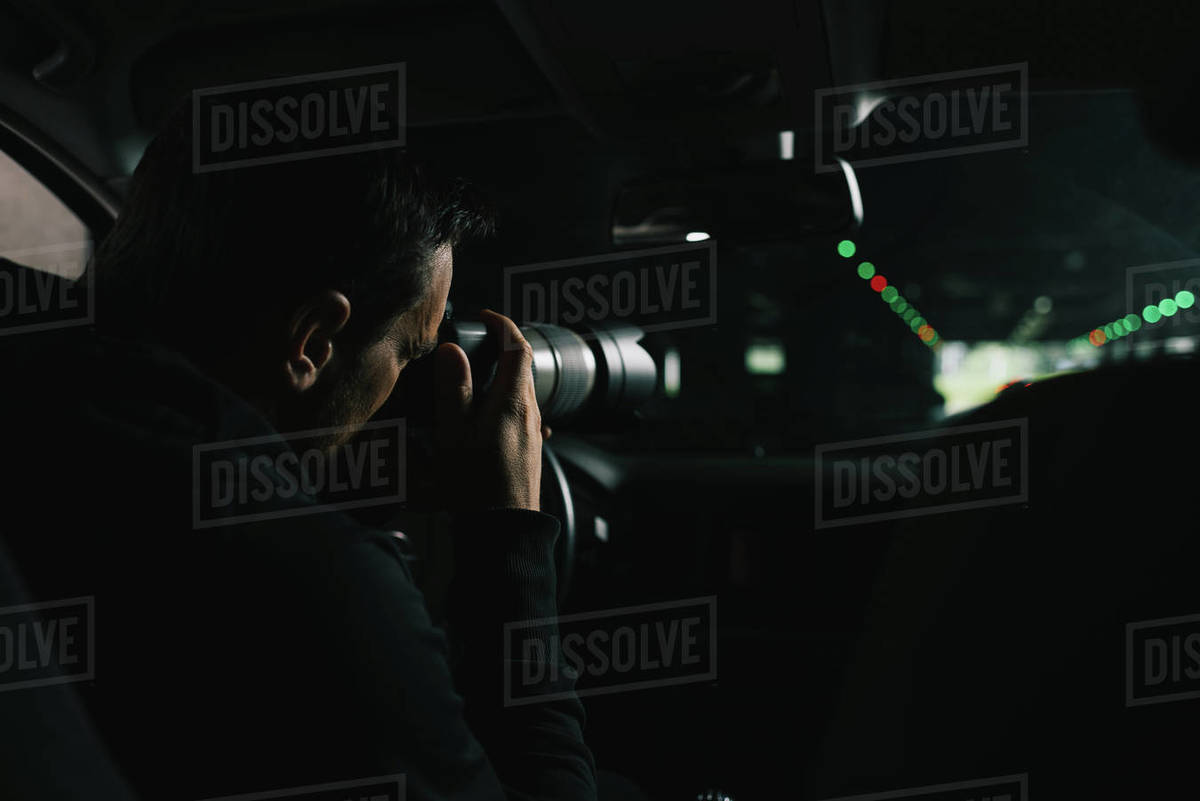 Back view of focused man doing surveillance by camera with object glass ...