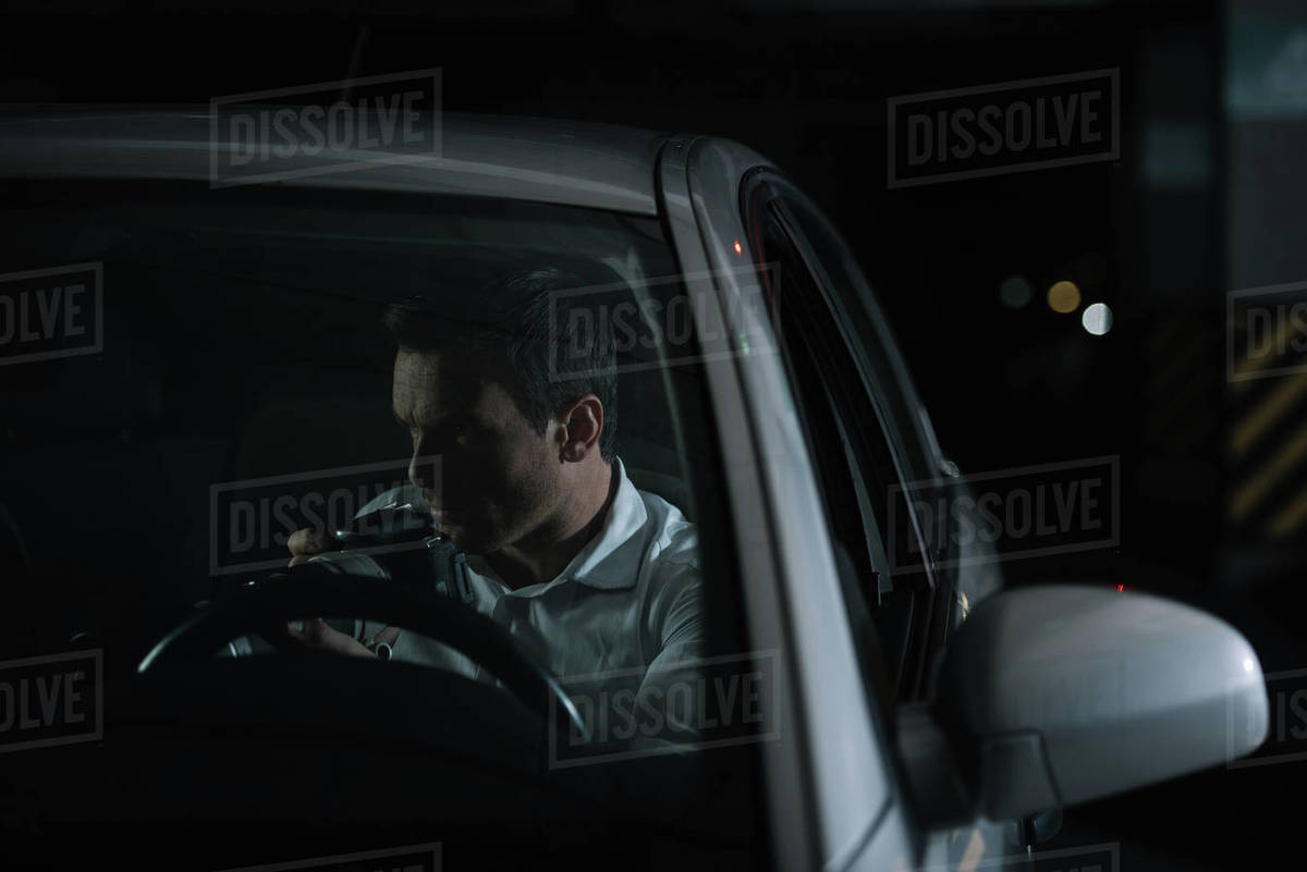 Serious undercover male agent doing surveillance by camera from his car ...