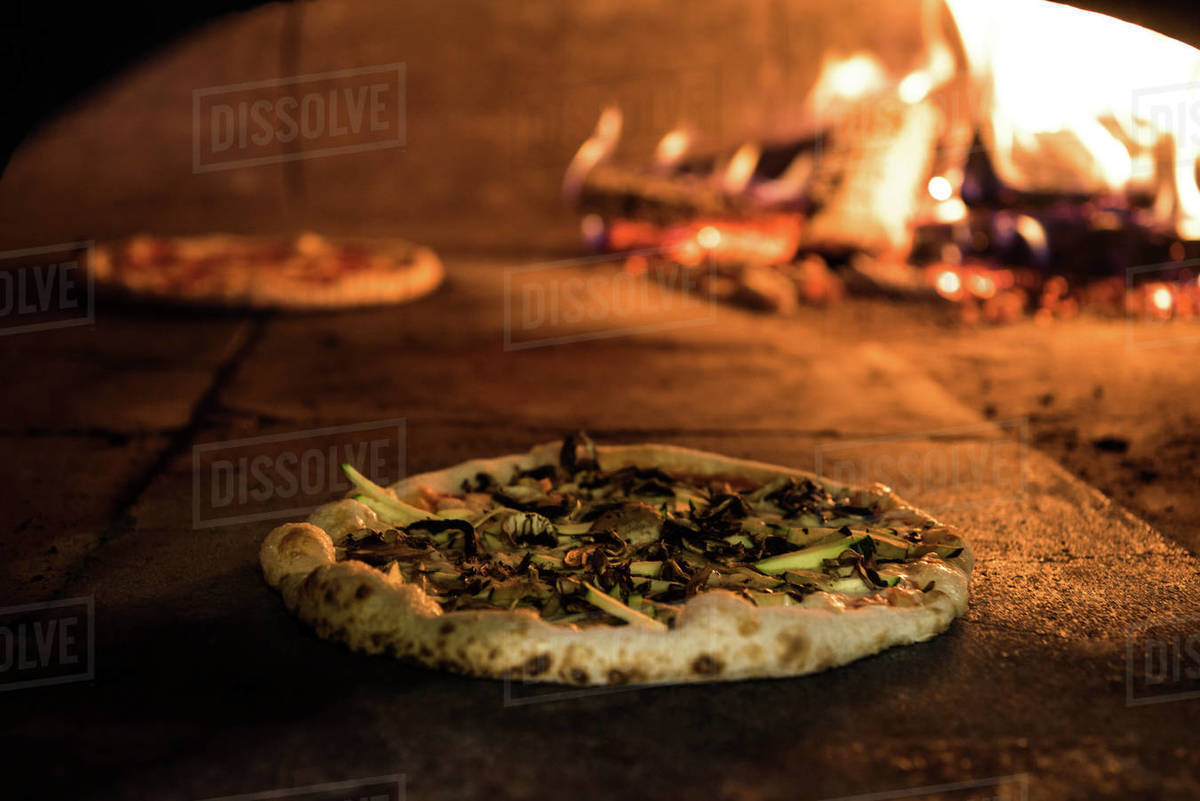 Close up view of italian pizza baking in brick oven in restaurant ...