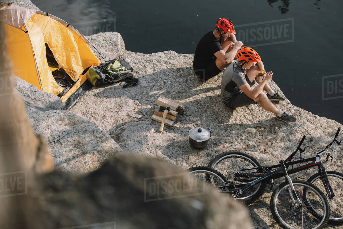 High angle view of active bike travelers eating canned food in camping ...