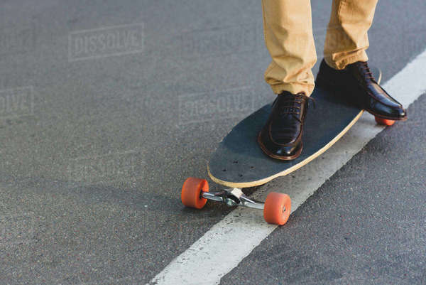 Cropped shot of young man standing on skateboard on street - Royalty ...
