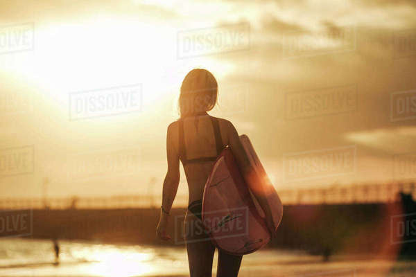 Back view of female surfer posing with surfboard at sunset - Royalty ...