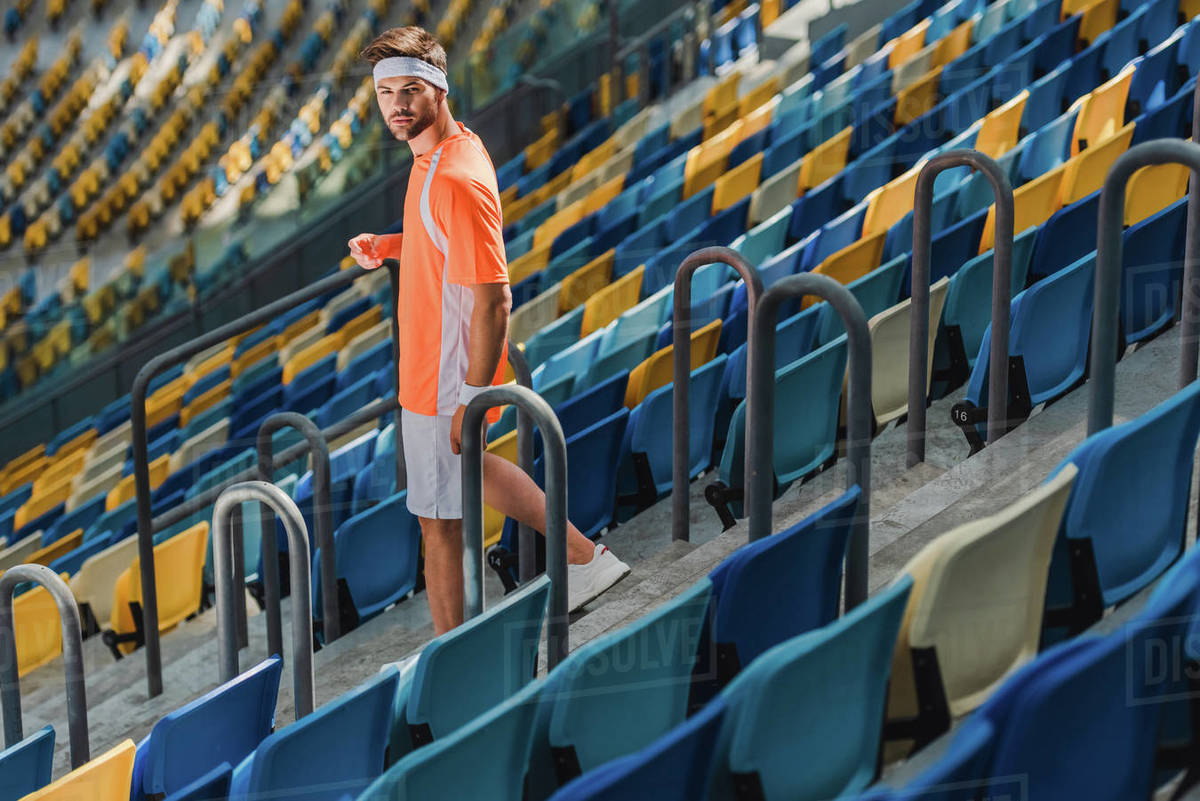 Sportive young man walking downstairs on stairs at sports stadium ...