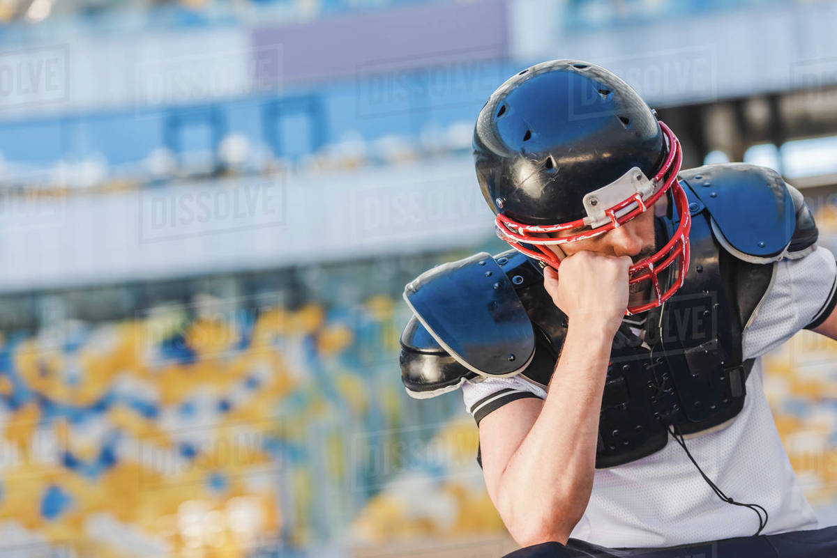 Sad young american football player sitting at sports stadium - Royalty ...