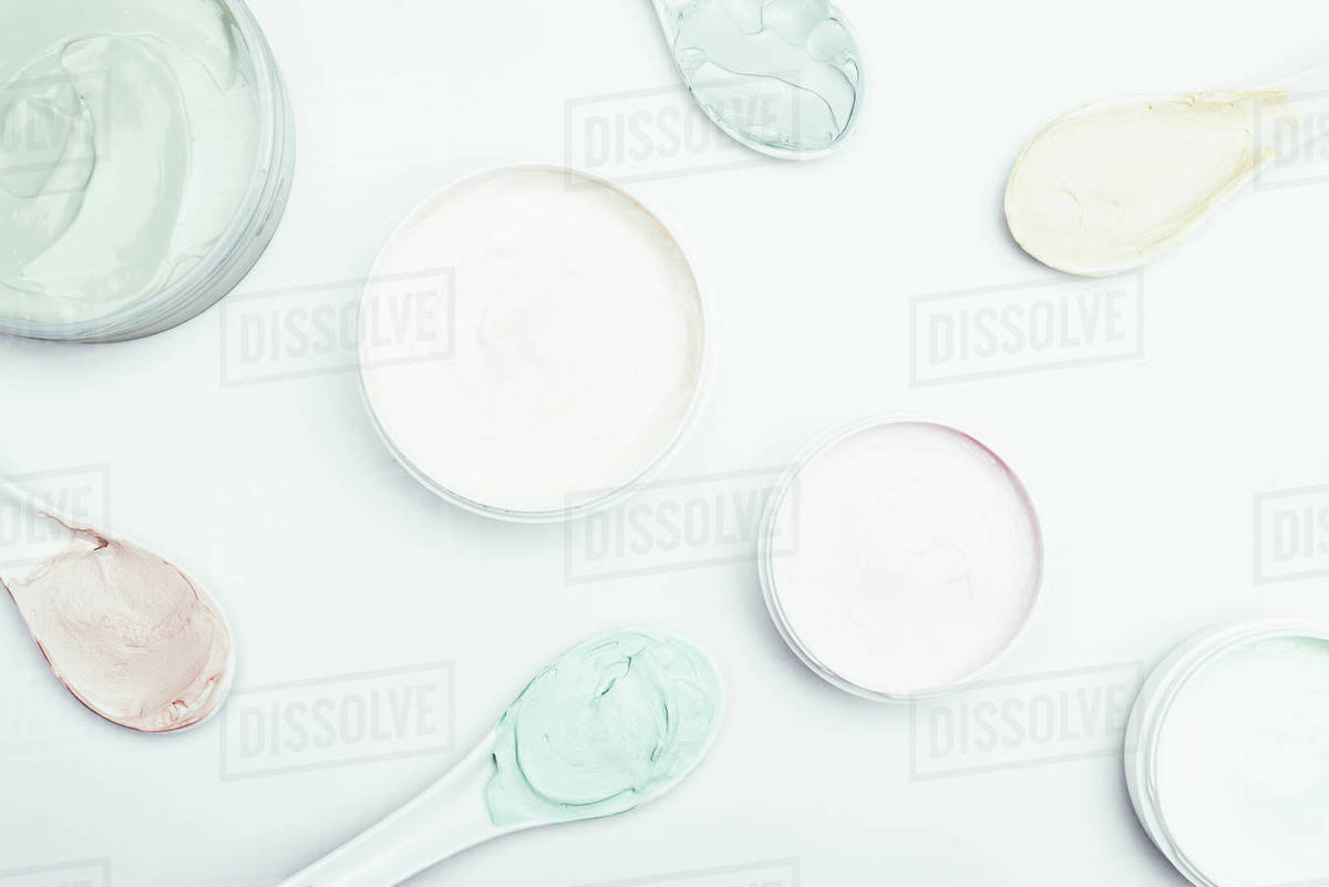 Flat lay with various clay masks in containers and spoons isolated on ...