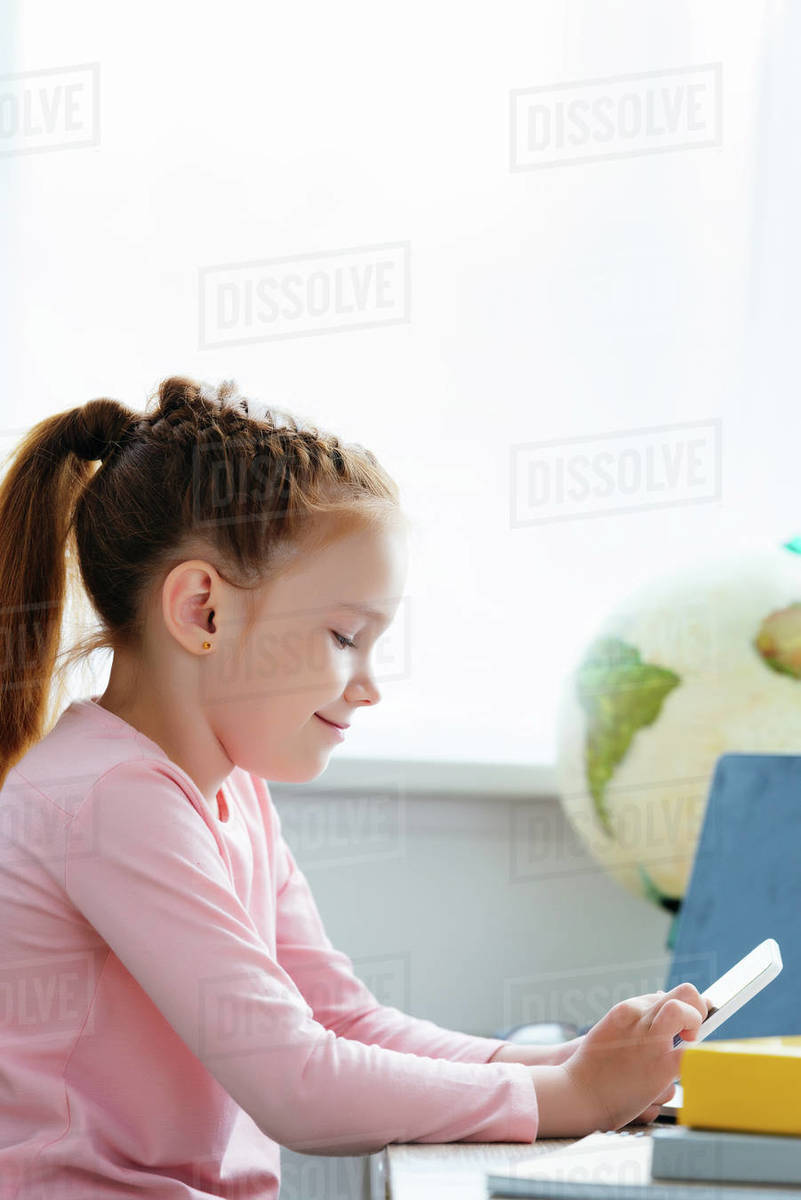 side view of beautiful smiling child using smartphone - Royalty-free ...