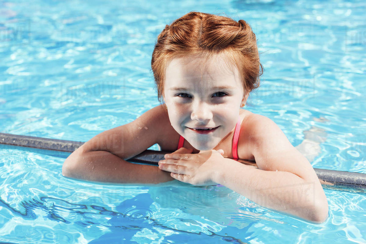 close-up portrait of happy little child in bikini in swimming pool ...