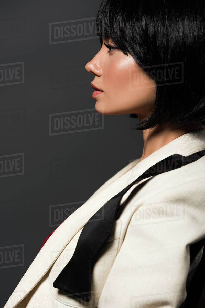 side view of attractive young woman in stylish jacket and untied bowtie ...