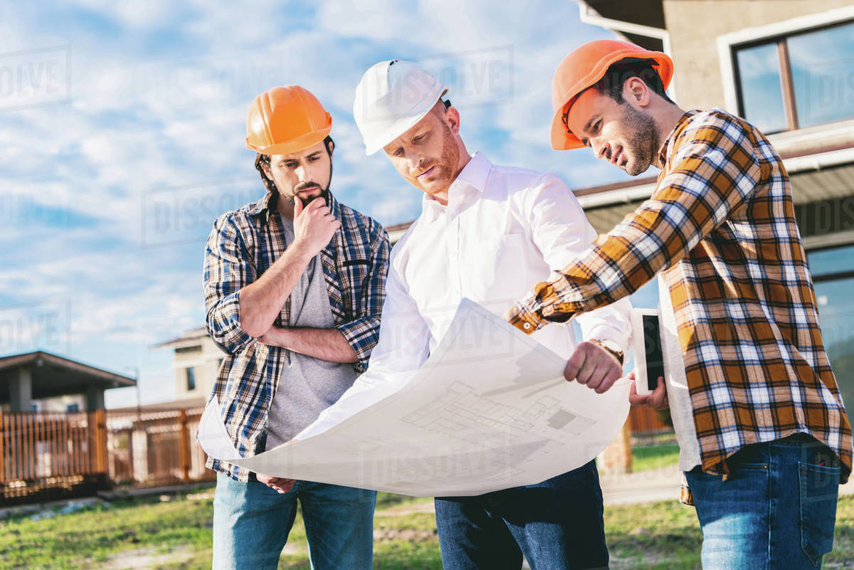 Group of handsome architects with blueprint in garden at construction ...