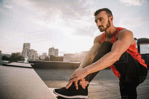 Handsome sportsman stretching legs on roof during sunset - Stock Photo ...