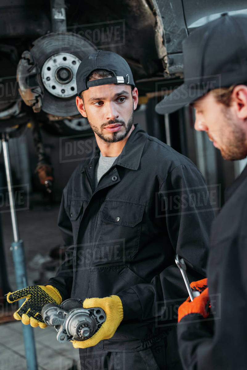 Professional mechanics in uniform working with car and tools in ...