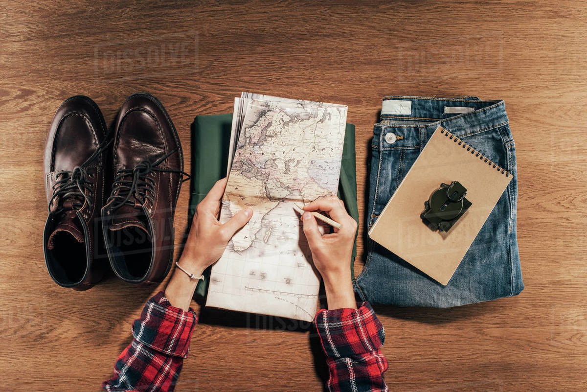 partial top view of person holding map and traveler set on wooden table ...