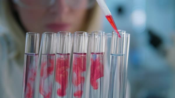 Close-up of chemical reaction - pipetting pink solution in glass test ...