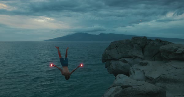 Extreme sports cliff diver doing a backflip off of a sea cliff with ...