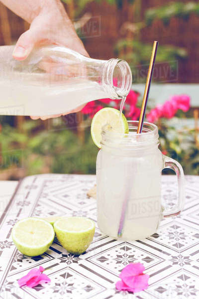 Close-up of a woman pouring a glass of frozen lemonade on a garden ...